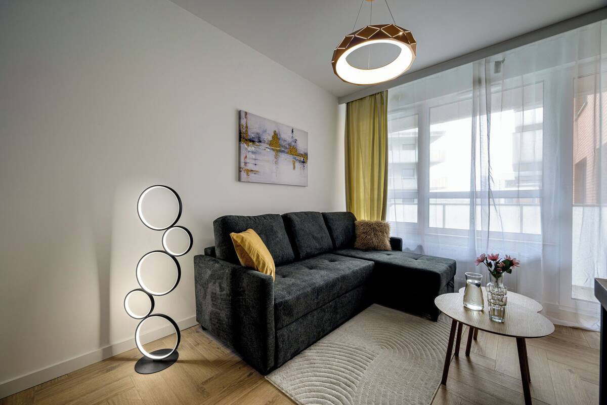 Uma sala de estar moderna com sofá modular, mesa de centro redonda e abajur.