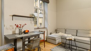 Uma sala de estar moderna com uma mesa de jantar, cadeiras, um sofá e uma pequena mesa lateral.