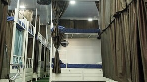 Quarto com beliches, cortinas, ventoinha no teto e piso de azulejos.