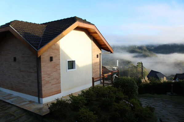 Uma casa com telhado inclinado, fachada de tijolos e uma janela pequena.