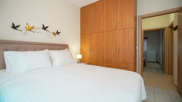 Quarto com cama grande, guarda-roupa de madeira e uma obra de arte na parede.