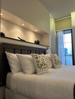 Cama bem arrumada com roupa de cama branca e dois travesseiros decorativos com motivos florais.