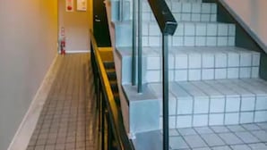 Uma escadaria com piso de azulejos e corrimão de metal.