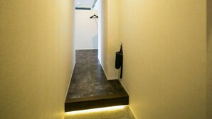 Um corredor estreito com piso escuro e uma faixa de luz na parte inferior.