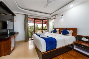 Quarto de hotel com uma cama, escrivaninha, televisão e ar condicionado.