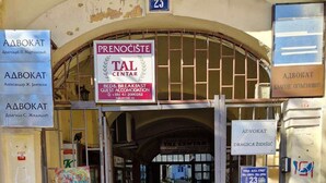 Entrada de edifício com placas indicando 'ADVOKAT' e 'TAL CENTAR', sinalizando um centro de negócios.
