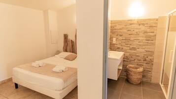 Quarto de hotel com uma cama, banheiro com pia e chuveiro.