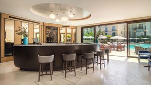 Uma área de bar moderna com teto curvo, banquetas e vista para uma área de piscina externa.