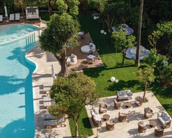 Vista aérea de um resort com piscina, áreas de descanso e mobiliário externo.