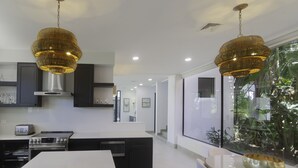 Uma cozinha moderna com ilha central, eletrodomésticos de aço inoxidável e iluminação pendente.
