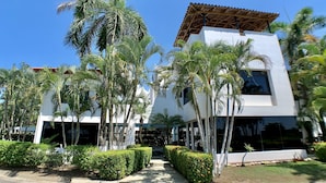 Um edifício moderno com fachada branca, várias janelas e telhado em telhas.