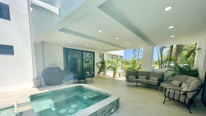 Área interna de piscina moderna com hidromassagem, assentos e plantas em vasos.