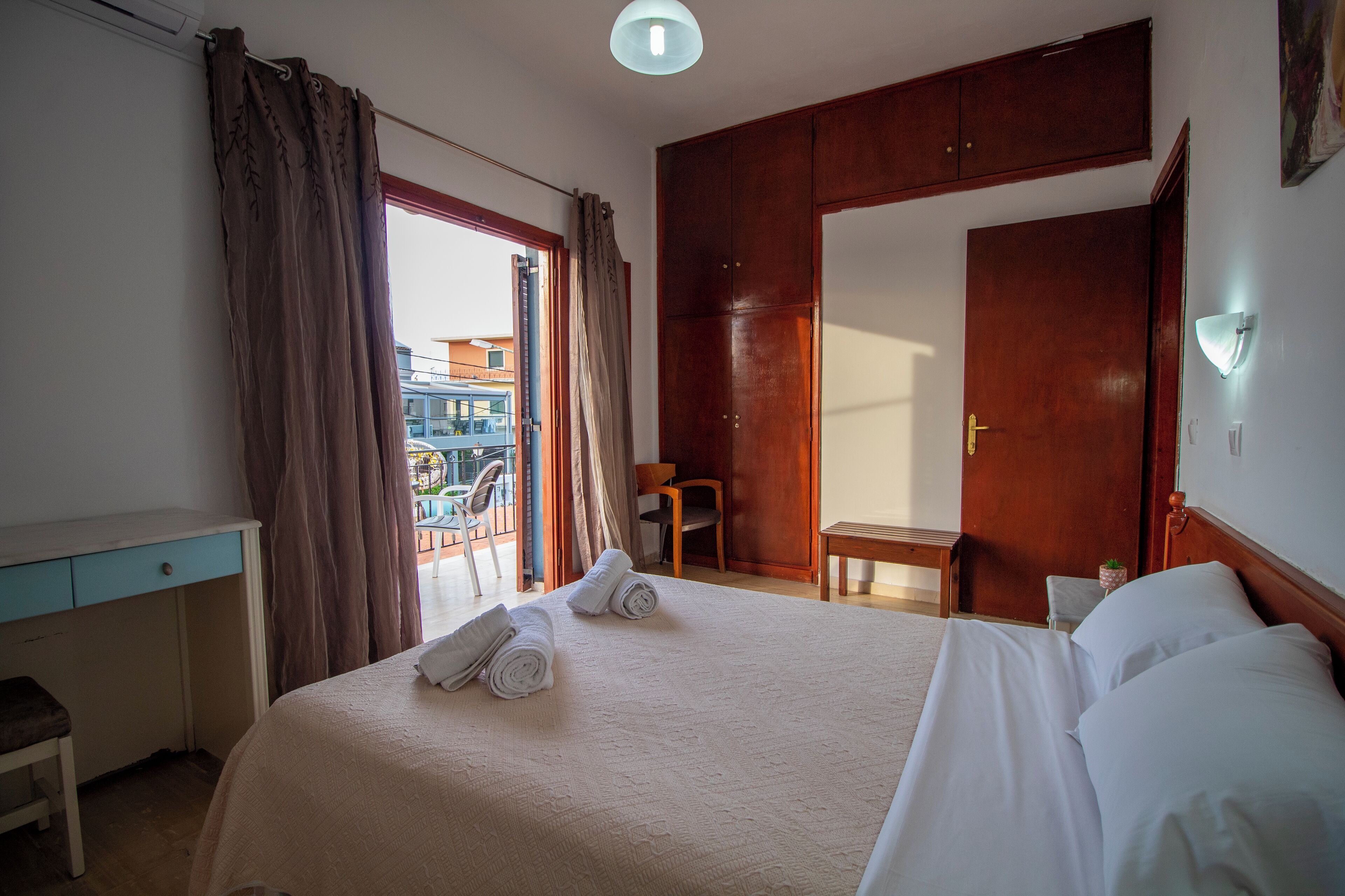 Quarto de hotel com cama, escrivaninha, cadeira e vista para o exterior.