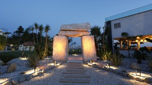 Um arco de pedra com a inscrição "GLENN" que dá acesso a um edifício moderno com fachada branca e área de estar ao ar livre.