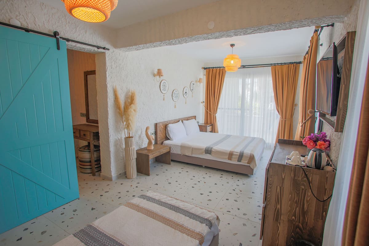 Um quarto com cama, mesas de cabeceira, cômoda, espelho e porta.