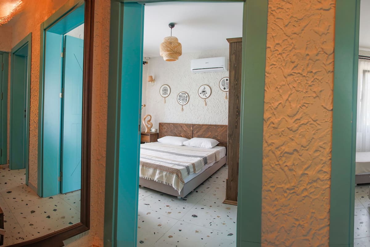Quarto de hotel com cama, mesa de cabeceira, espelho e ar condicionado fixado na parede.