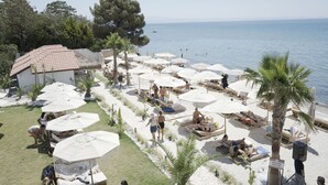 Resort à beira-mar com espreguiçadeiras e guarda-sóis, área de piscina e vista para o mar.