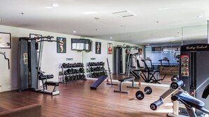 Uma academia com diversos equipamentos de exercícios, incluindo aparelhos de musculação, halteres e esteira.