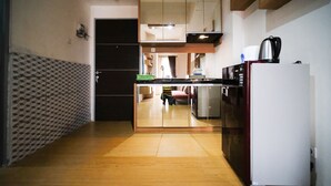 Cozinha equipada com frigorífico, forno e micro-ondas. Apresenta uma parede com padrão decorativo e uma porta que dá para outro espaço.