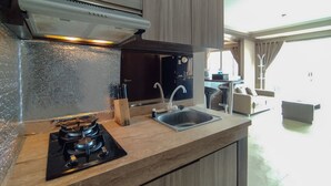 Cozinha moderna com fogão a gás, pia e micro-ondas. Há uma área de refeições com um sofá e uma mesa ao fundo.