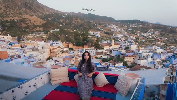 Uma pessoa sentada em um terraço no telhado com vista para a cidade.