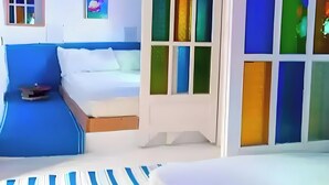 Um quarto com uma cama, um sofá azul e uma janela com vitrais coloridos.