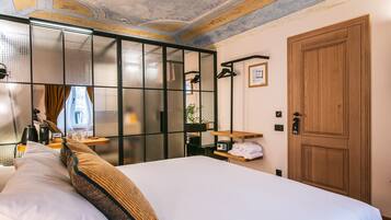 Quarto de hotel com uma cama, um guarda-roupa de madeira, um espelho, uma prateleira com produtos de higiene pessoal e teto decorativo.