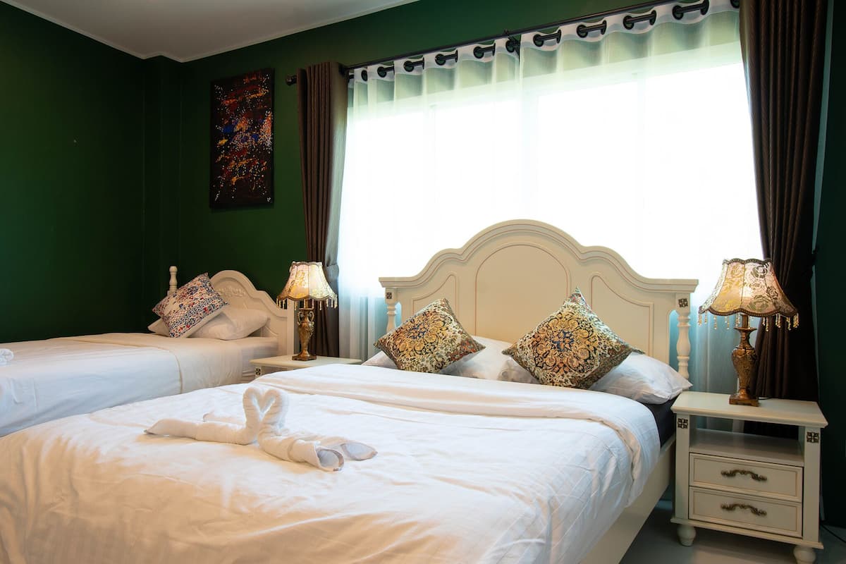 Quarto de hotel com duas camas, mesa de cabeceira, luminárias e um quadro na parede.