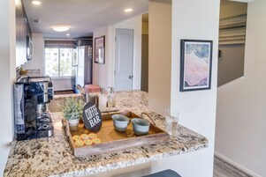 Uma cozinha com cafeteira, uma bandeja com xícaras de café e uma placa que diz 'COFFEE BAR'.