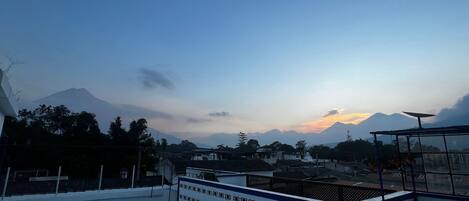 Terraço no telhado com vista para uma cordilheira durante o pôr do sol.