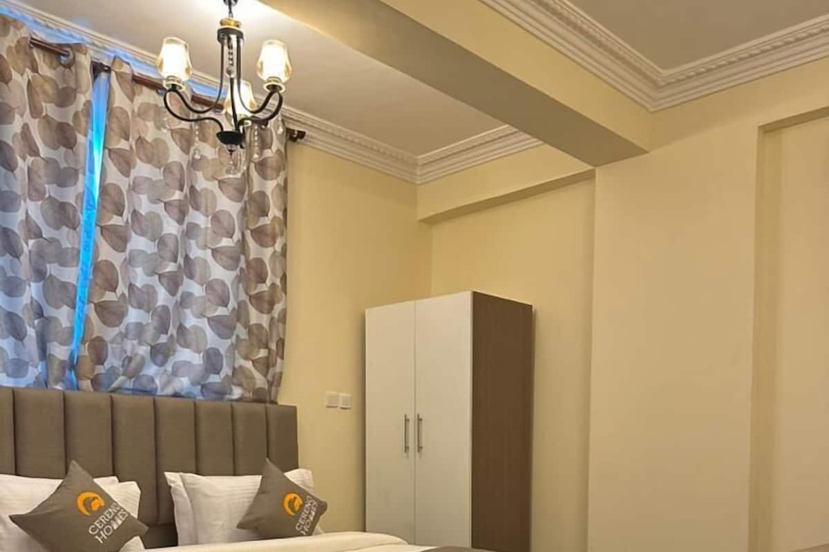 Quarto de hotel moderno com uma cama grande, um guarda-roupa e um candelabro.