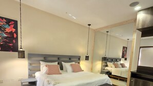 Quarto moderno com uma cama grande, um banquinho, um espelho e um quadro na parede.