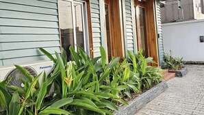 Um edifício com fachada verde, duas portas de madeira e um aparelho de ar condicionado visível.