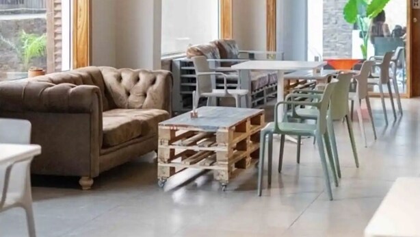 Um interior moderno com sofá, mesa de jantar, cadeiras e luminárias pendentes.