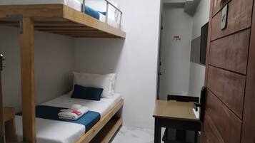 Uma cama de beliche com escrivaninha e televisão num quarto pequeno.