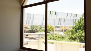 Quarto com uma grande janela arqueada com vista para um edifício moderno e áreas verdes.