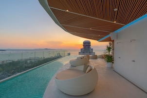 Uma piscina no terraço com vista para o pôr do sol e para a paisagem urbana.