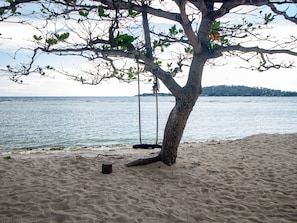 Na praia, praia de areia branca, espreguiçadeiras, guarda-sóis de praia