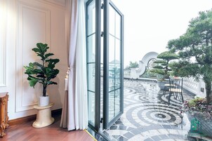 Quarto com uma grande porta de vidro que dá para uma área externa com piso ladrilhado e um jardim.