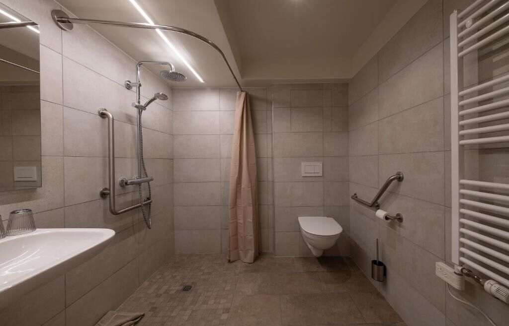 Uma casa de banho moderna com chuveiro, sanita e lavatório.