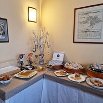 Disposição de buffet com diversos alimentos, um vaso decorativo e quadros nas paredes.
