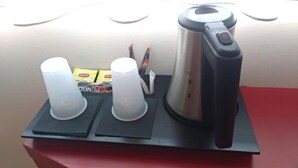 Uma cafeteira com duas chávenas brancas sobre um tabuleiro preto.
