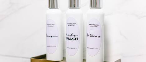 Três garrafas de shampoo e condicionador artesanal em uma prateleira.