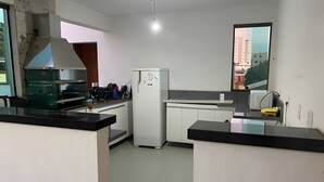 Cozinha moderna com armários brancos, bancada preta e geladeira.