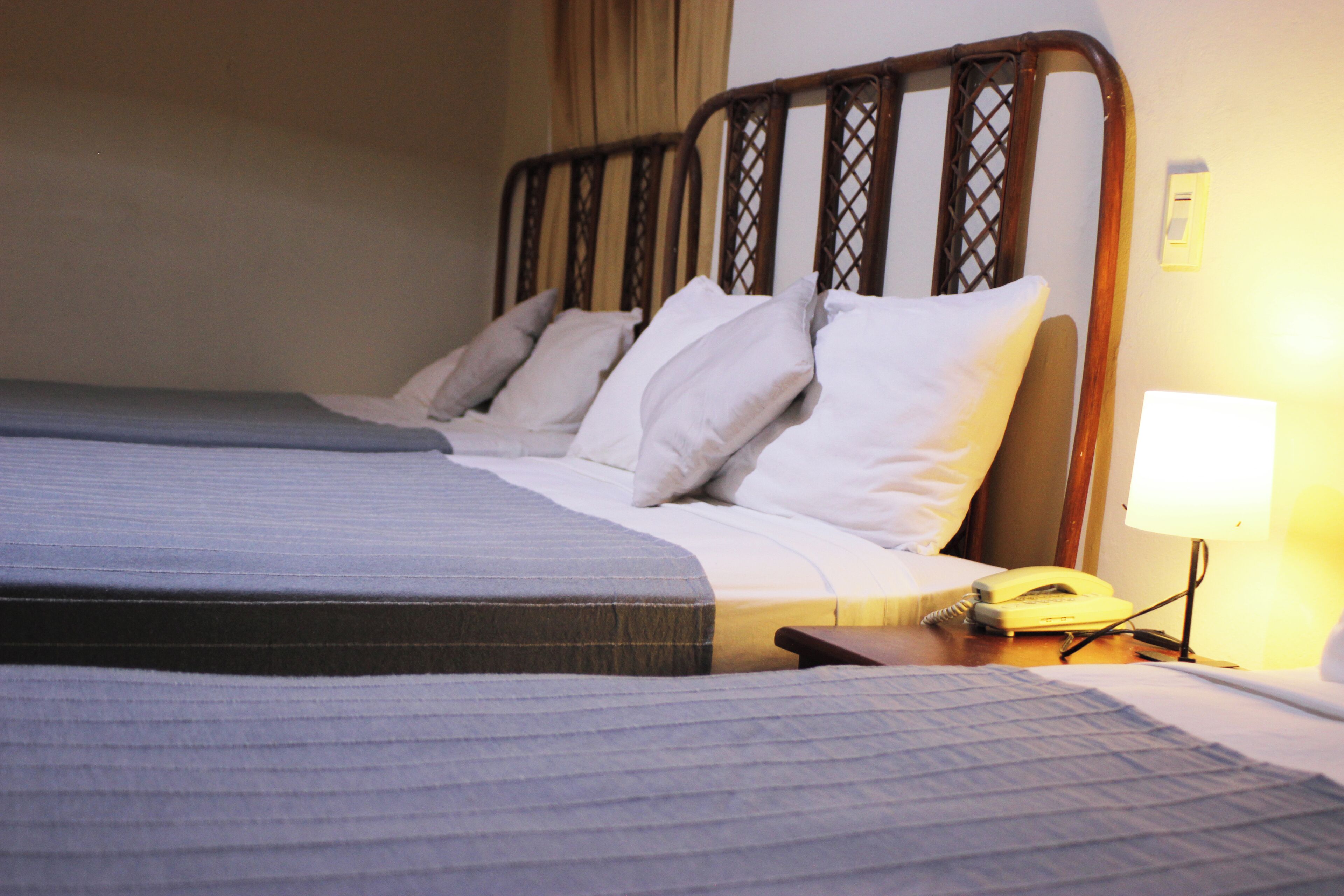 Quarto de hotel com duas camas, uma mesa de cabeceira com abajur e um telefone.