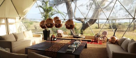 Um quarto com tenda, uma janela grande, um sofá, uma mesa de centro e decorações esféricas penduradas.