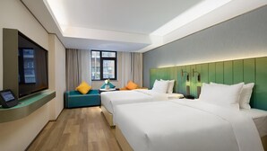 Quarto de hotel com duas camas, televisão, escrivaninha e janela com cortinas.