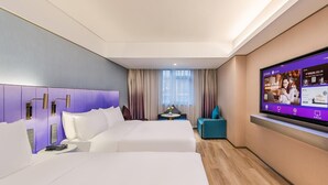 Quarto de hotel com duas camas, uma televisão presa à parede, uma mesinha e uma cadeira.