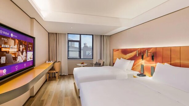 Quarto de hotel com duas camas, televisão, escrivaninha e janela com vista.
