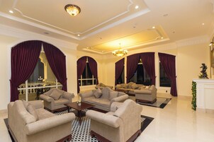 Uma sala de estar ampla, com teto alto, elegantes lustres e grandes janelas com cortinas decorativas.